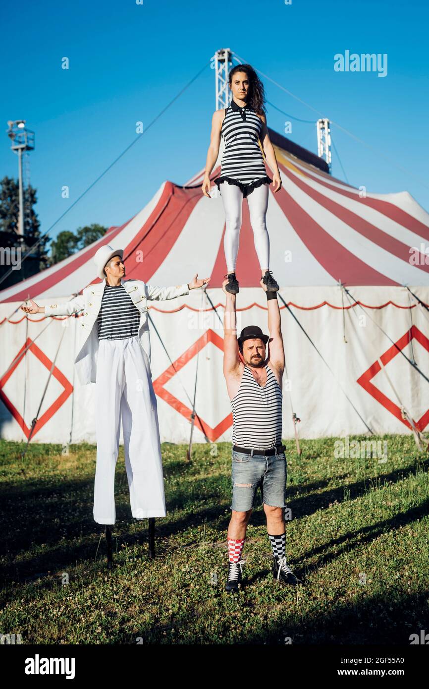Acrobats performing with artist while standing on meadow Stock Photo ...