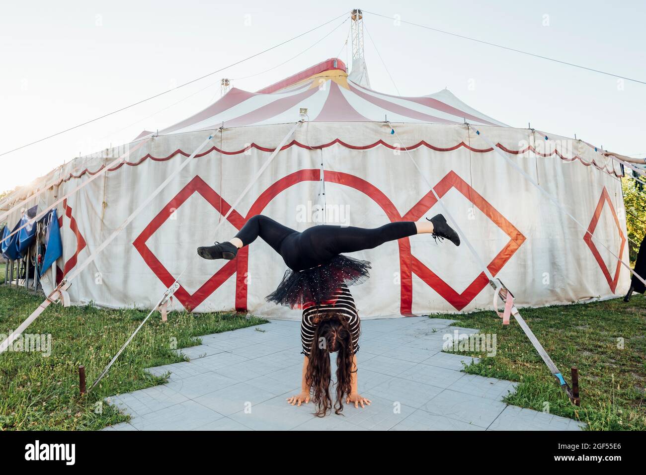 Female acrobat stretching legs while doing handstand on footpath Stock ...