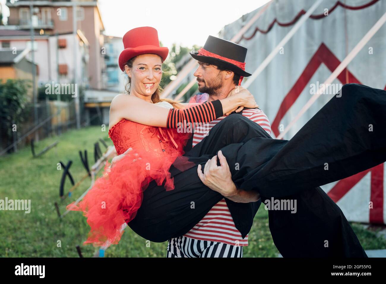 Male acrobat carrying female performer while standing outside circus ...
