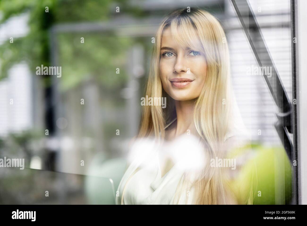 Beautiful female professional looking through glass window Stock Photo ...