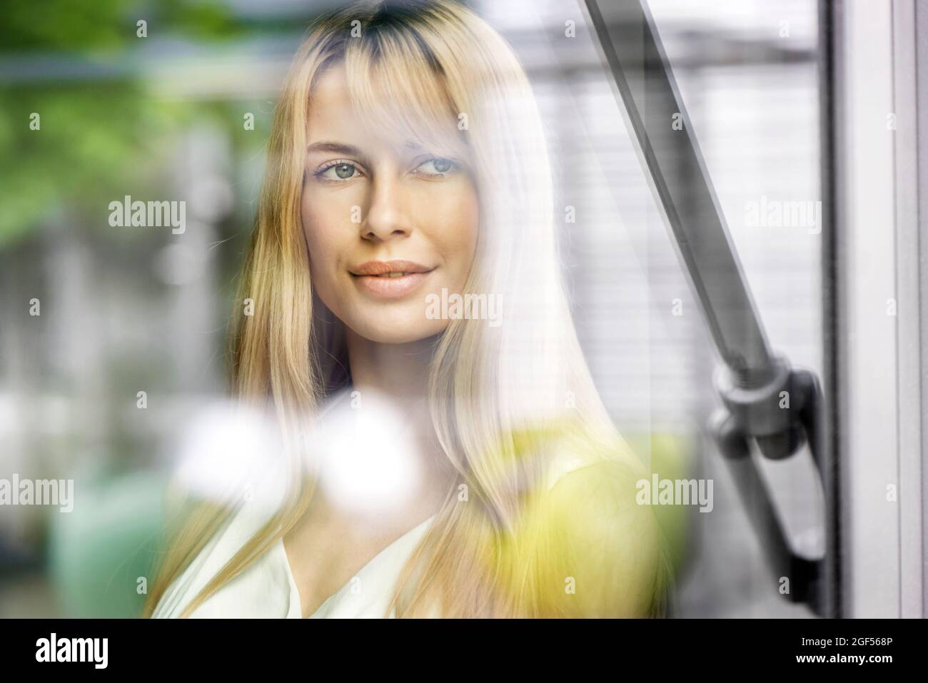 Contemplating female professional looking through glass Stock Photo - Alamy