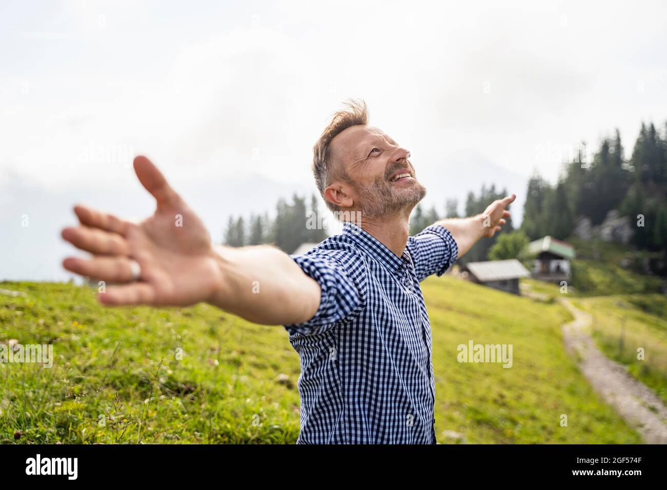 Happy man standing with arms outstretched on mountain Stock Photo - Alamy