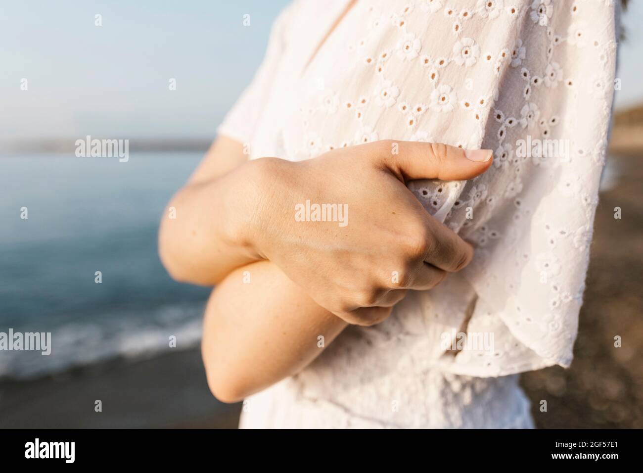 Young woman standing with arms crossed at beach Stock Photo - Alamy