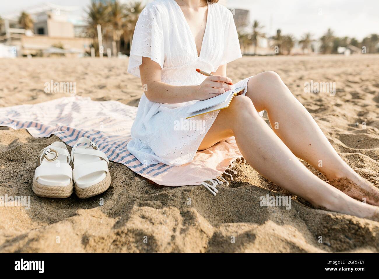 Woman writing in book while sitting at beach Stock Photo - Alamy