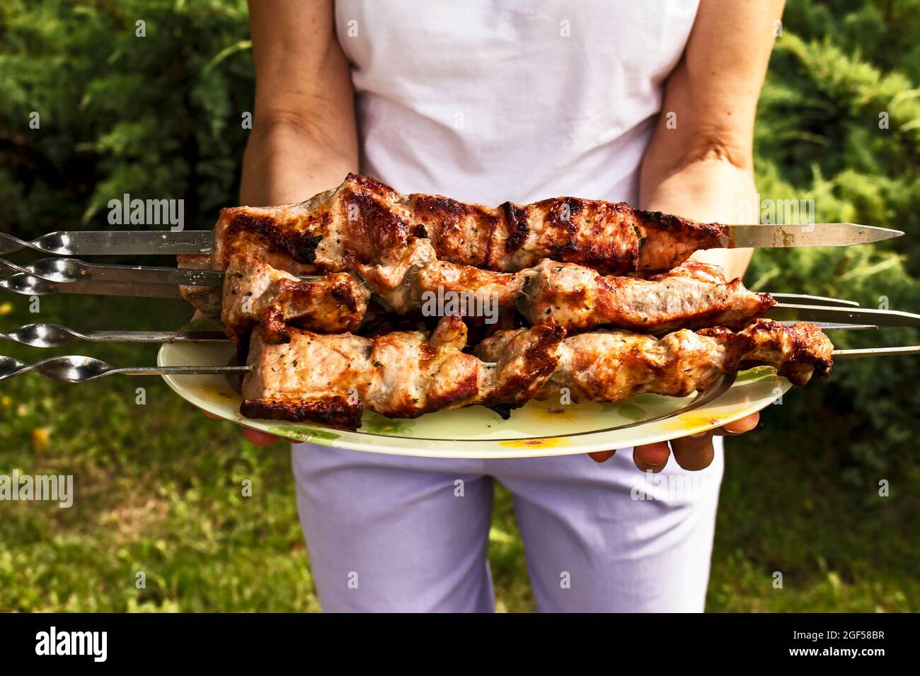 Woman holding cooked fried kebabs. The juicy pieces of meat are well ...