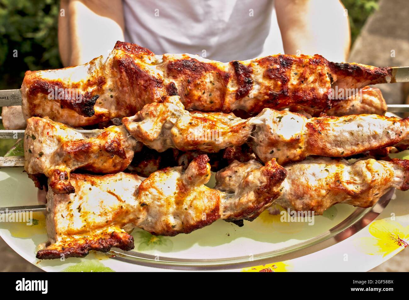 Woman holding cooked fried kebabs. The juicy pieces of meat are well ...
