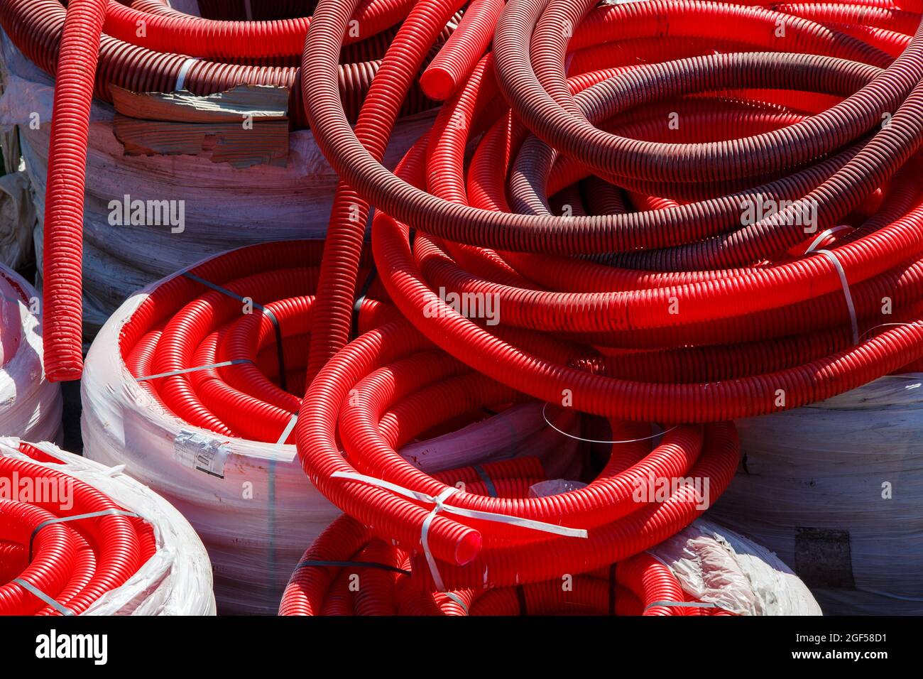 a pile of red corrugated PVC pipes for cable lay on the construction ...