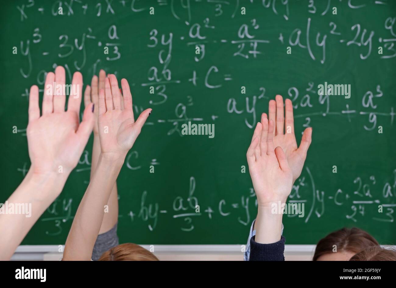 Raised hands on blackboard background in class Stock Photo - Alamy