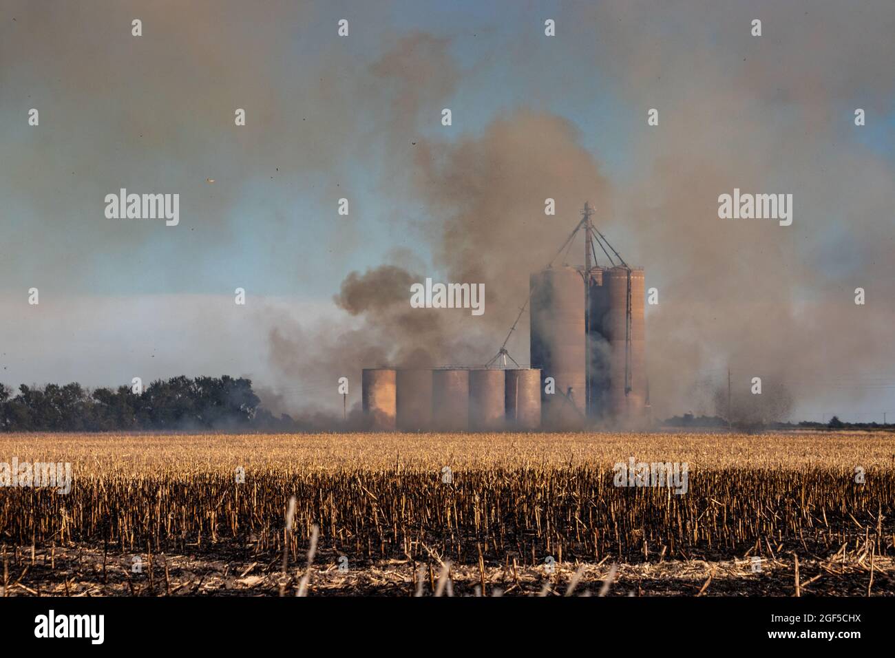 Wide angle landscape shot of a silo in a burning agriculture field of ...