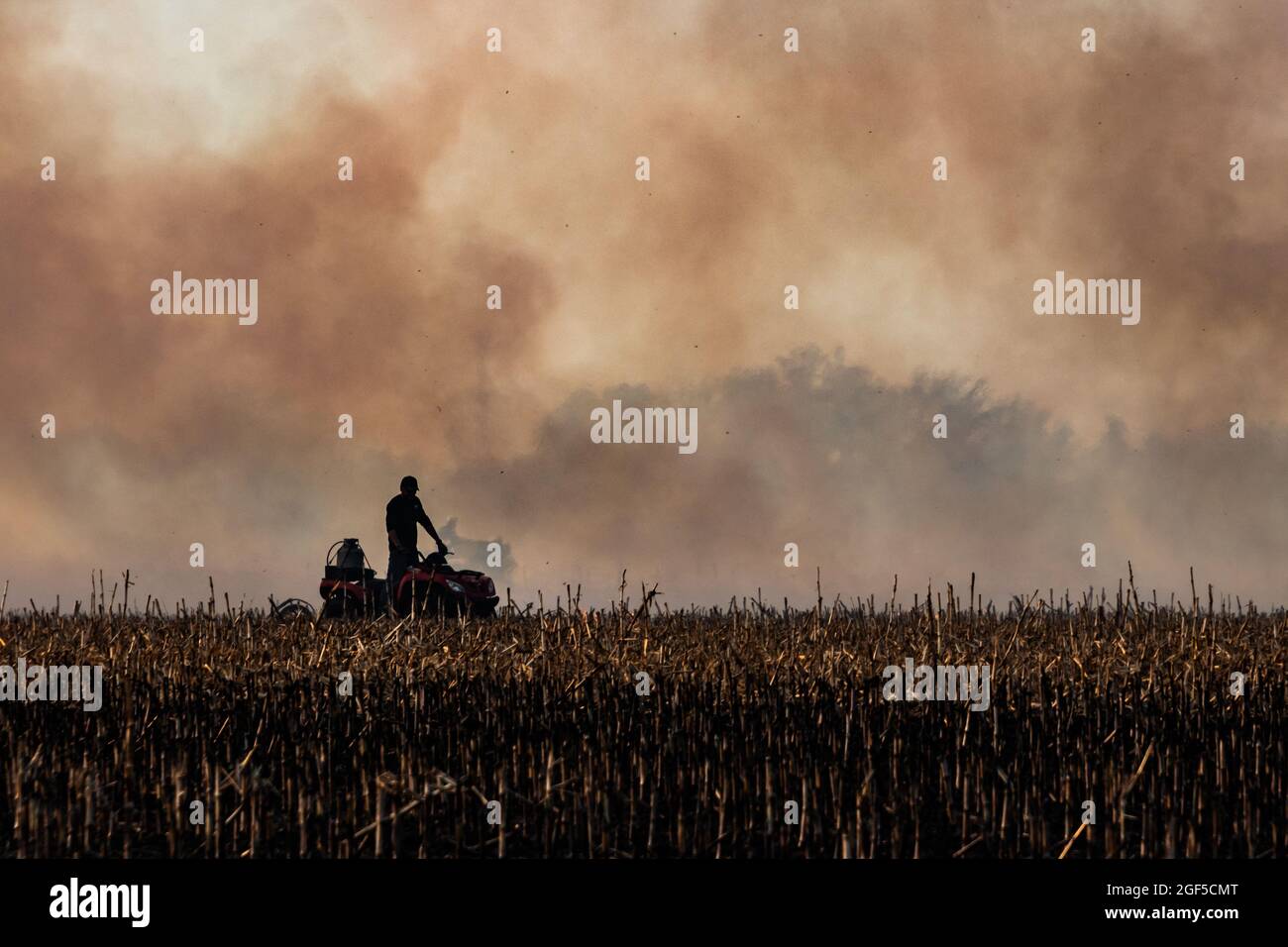 Anonymous farmer silhouette fighting fire in agricultural farming field ...