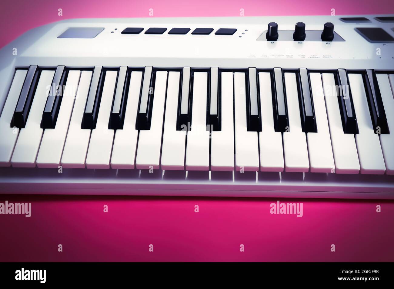 Keyboard of synthesizer on pink background Stock Photo - Alamy