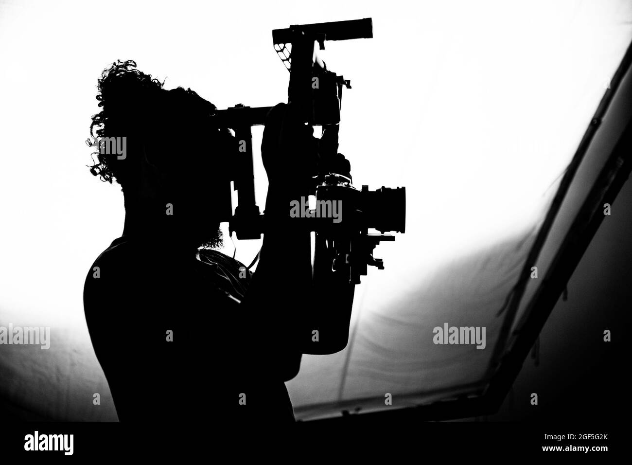 Silhouette of a cameraman holding a cinema camera on white background ...