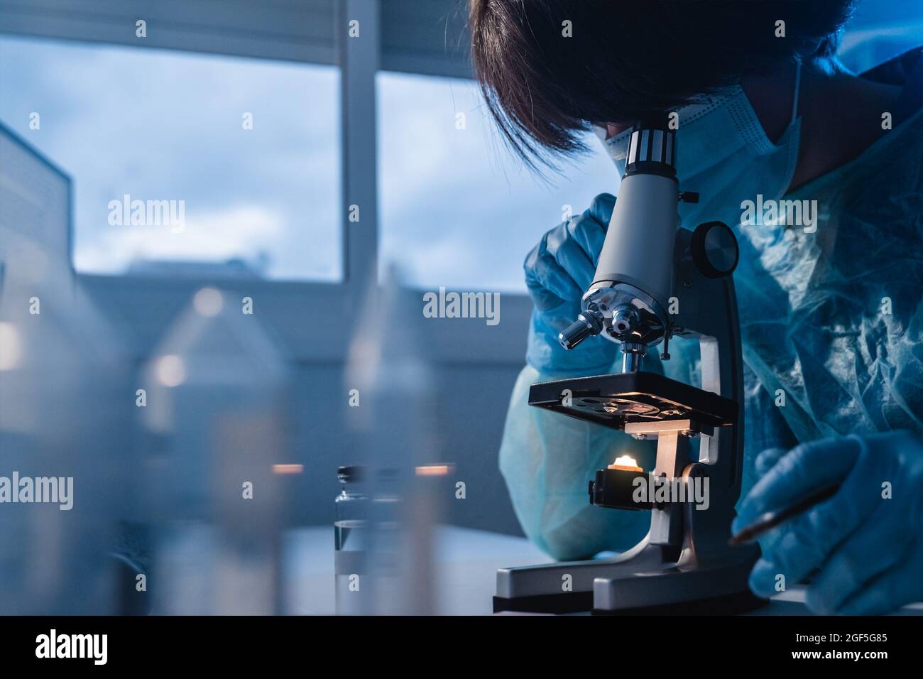 Asian medical scientist using microscope analyzing covid samples inside ...