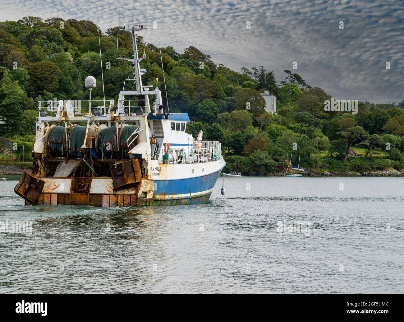 Trawler leaving harbour for fishing grounds, view of stern showing nets ...