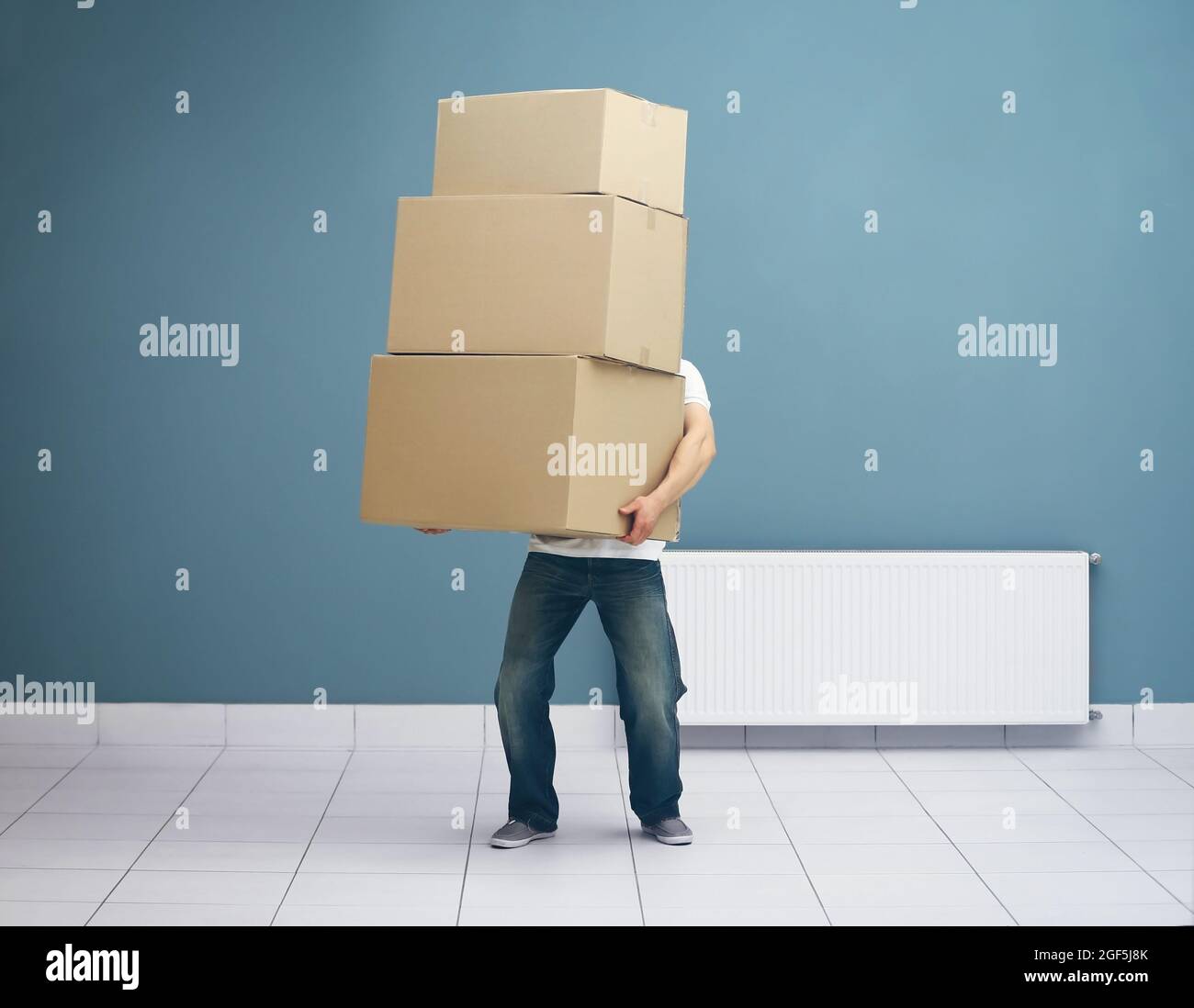 Man holding pile of carton boxes against blue wall in the room Stock ...