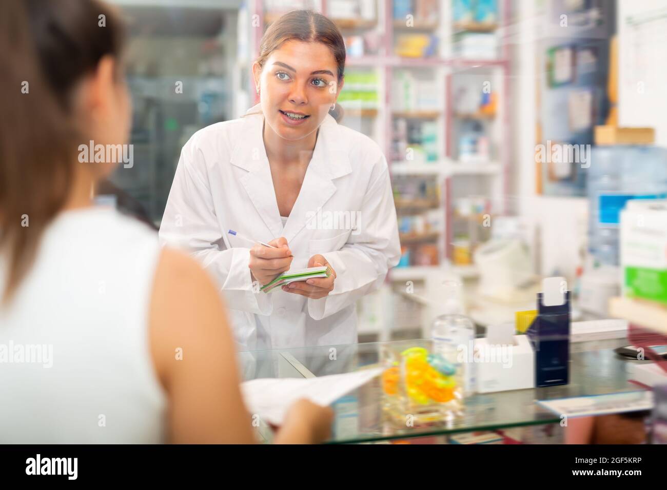 Pharmacist standing behind counter and talking with client Stock Photo ...