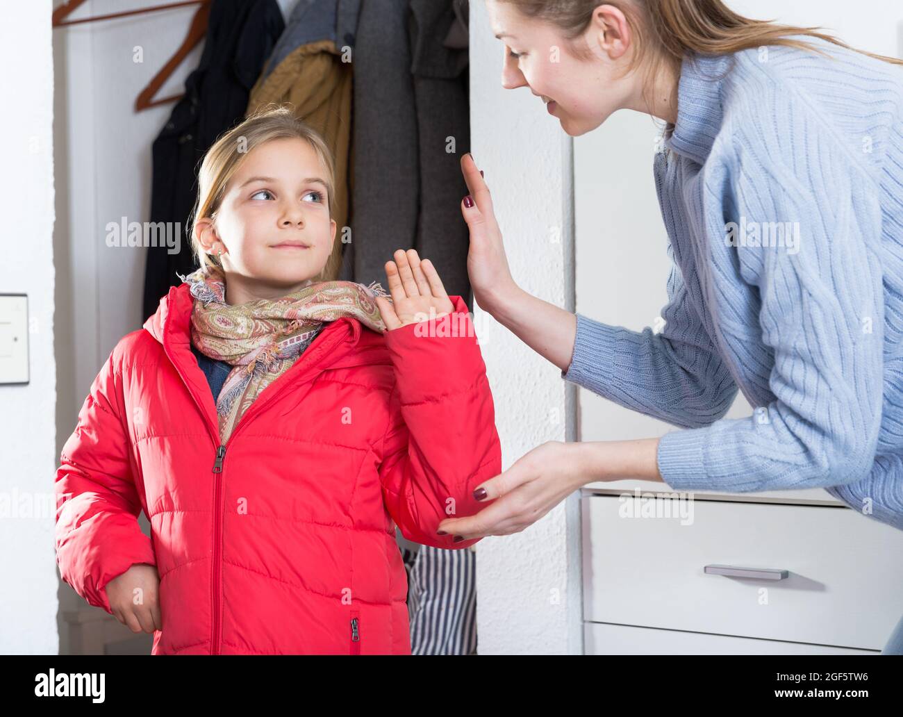 Mother says goodbye to her little daughter in the hallway at home Stock ...