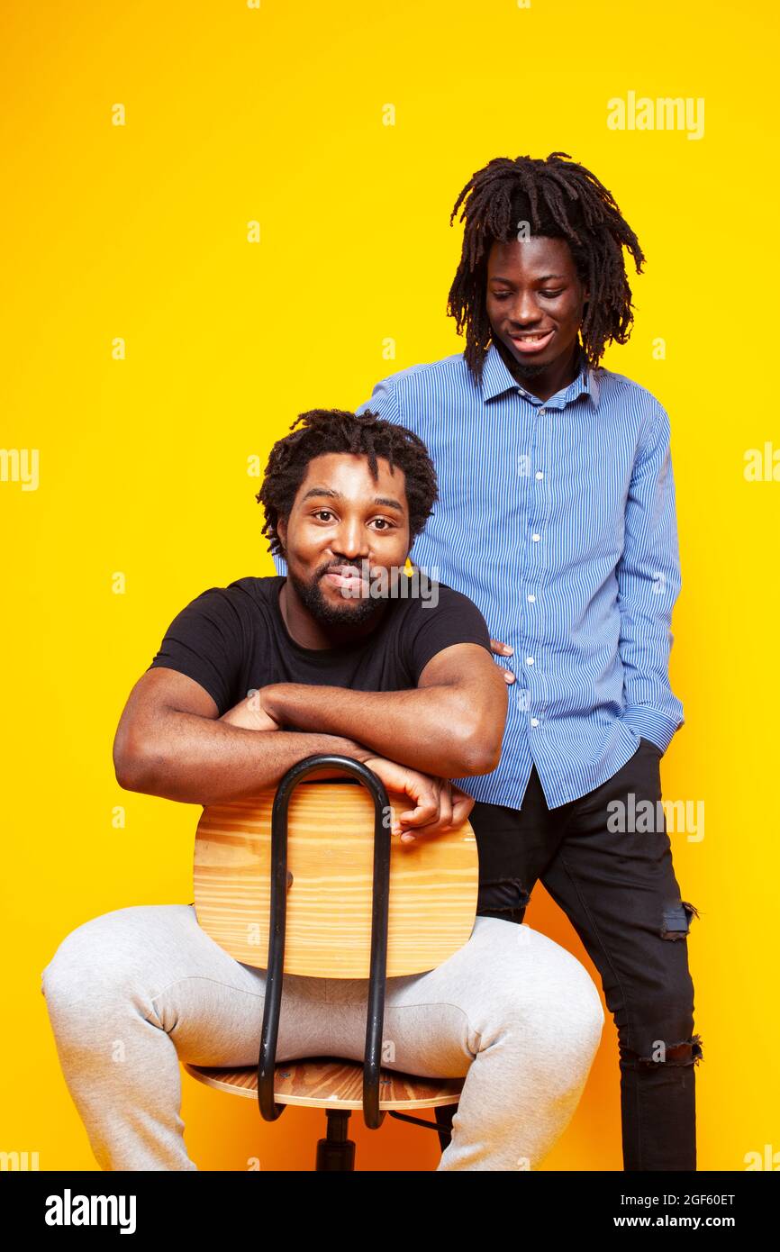 two african american guys posing cheerful together on yellow background ...