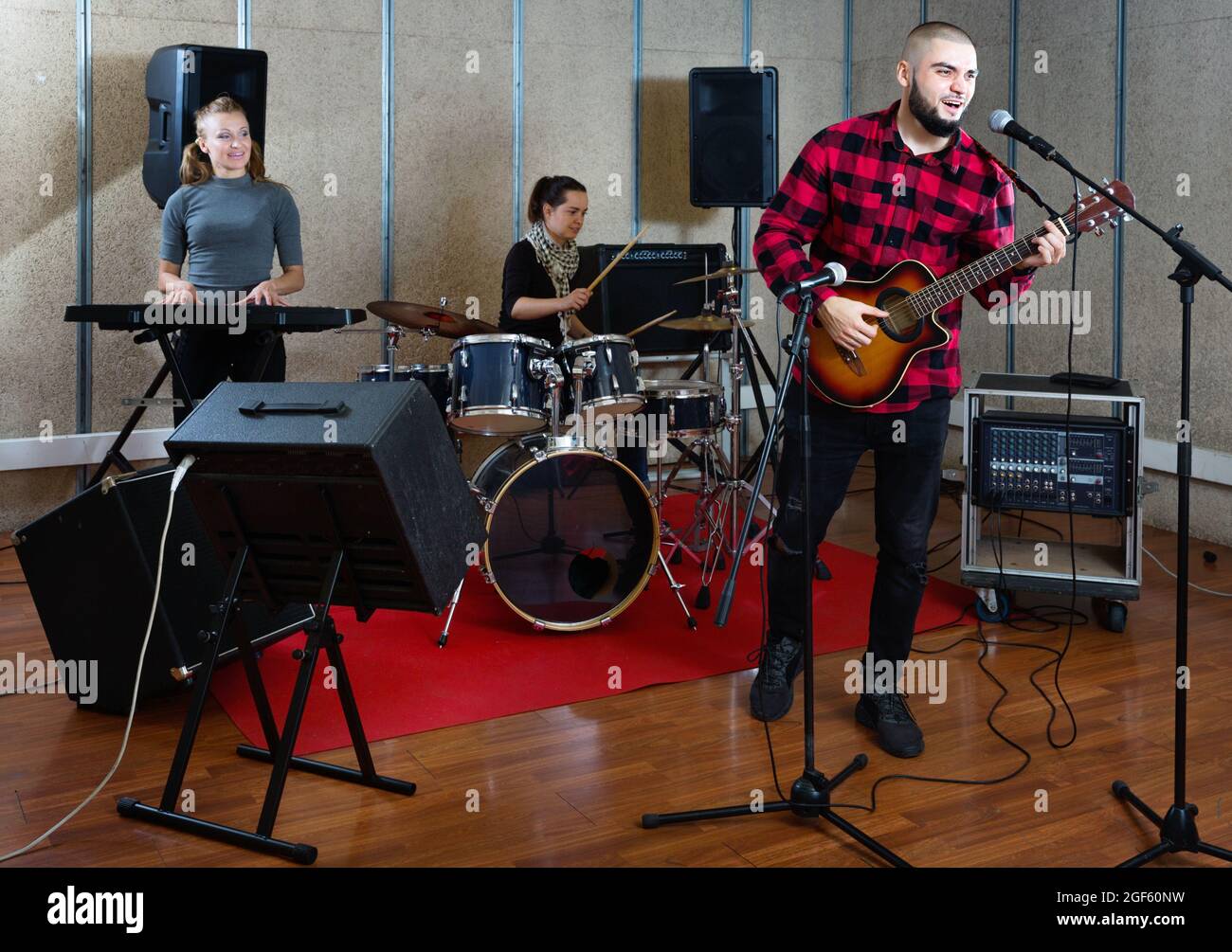 Guy guitar player and singer practicing with band members in recording ...