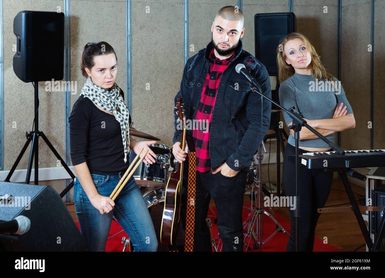 Three bandmates posing together with musical instruments in rehearsal ...