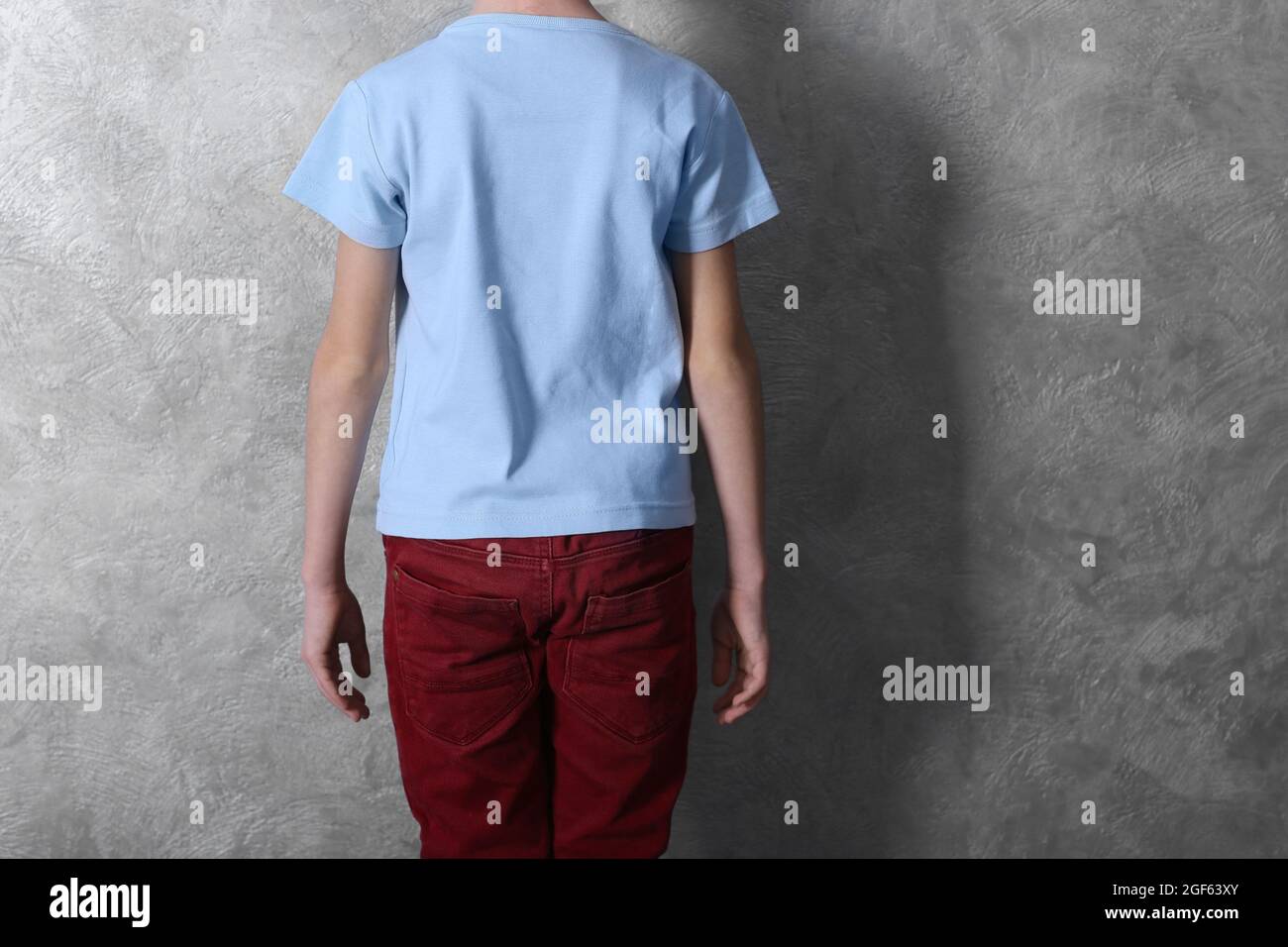 Clothes advertising. Boy in T-shirt and red trousers against grey ...