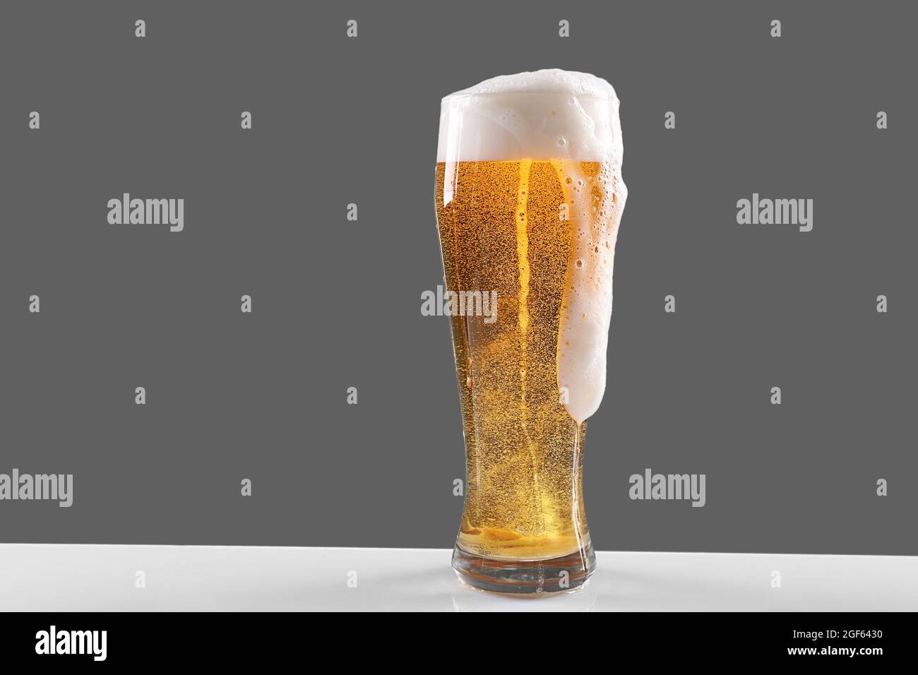 Glass of lager beer with thick froth on grey background Stock Photo - Alamy
