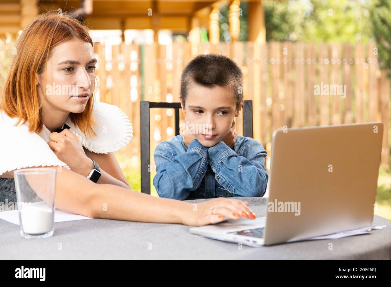 mom teaches the child at home in the garden, home schooling. Mom helps ...