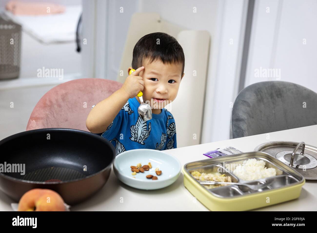 Asian boy boy holding a spoon and eating rice at home Stock Photo - Alamy