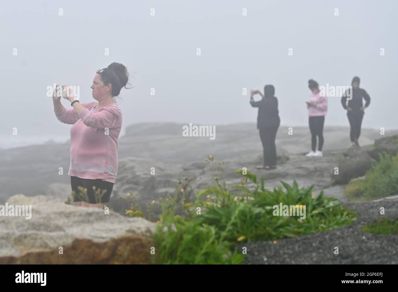 People watch and photograph the rough waters and heavy haze outside of ...