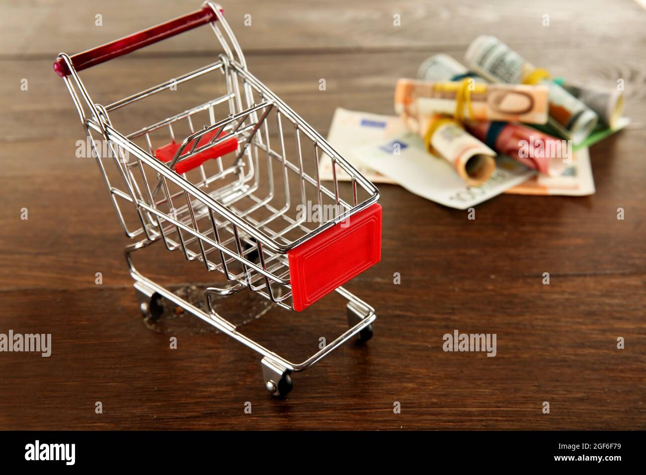 Small shopping trolley with euros banknotes on wooden background Stock ...
