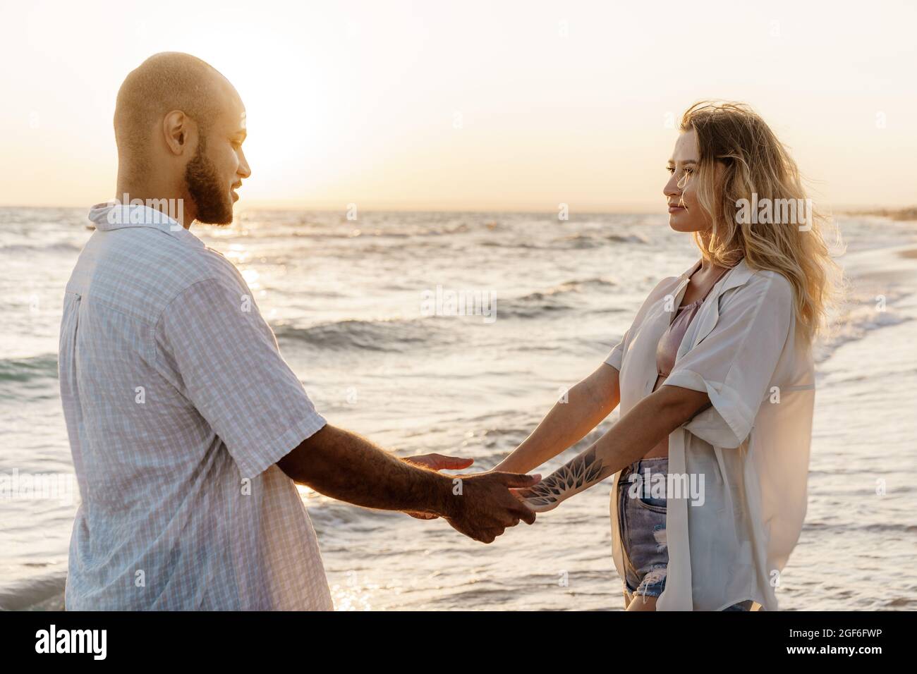 Portrait of happy young couple in love embracing each other on beach ...