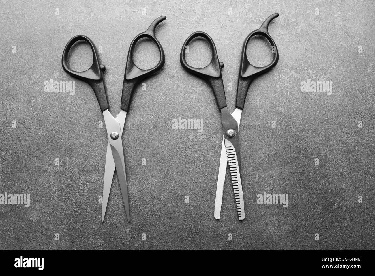 Professional scissors with black handles on a dark grey surface, top ...