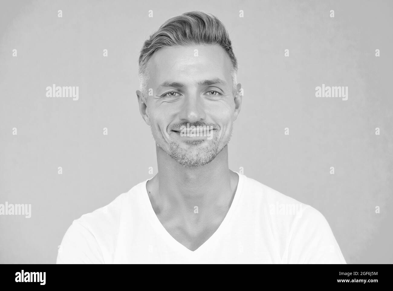 smiling guy with trendy hairstyle has colored graying hair and groomed ...