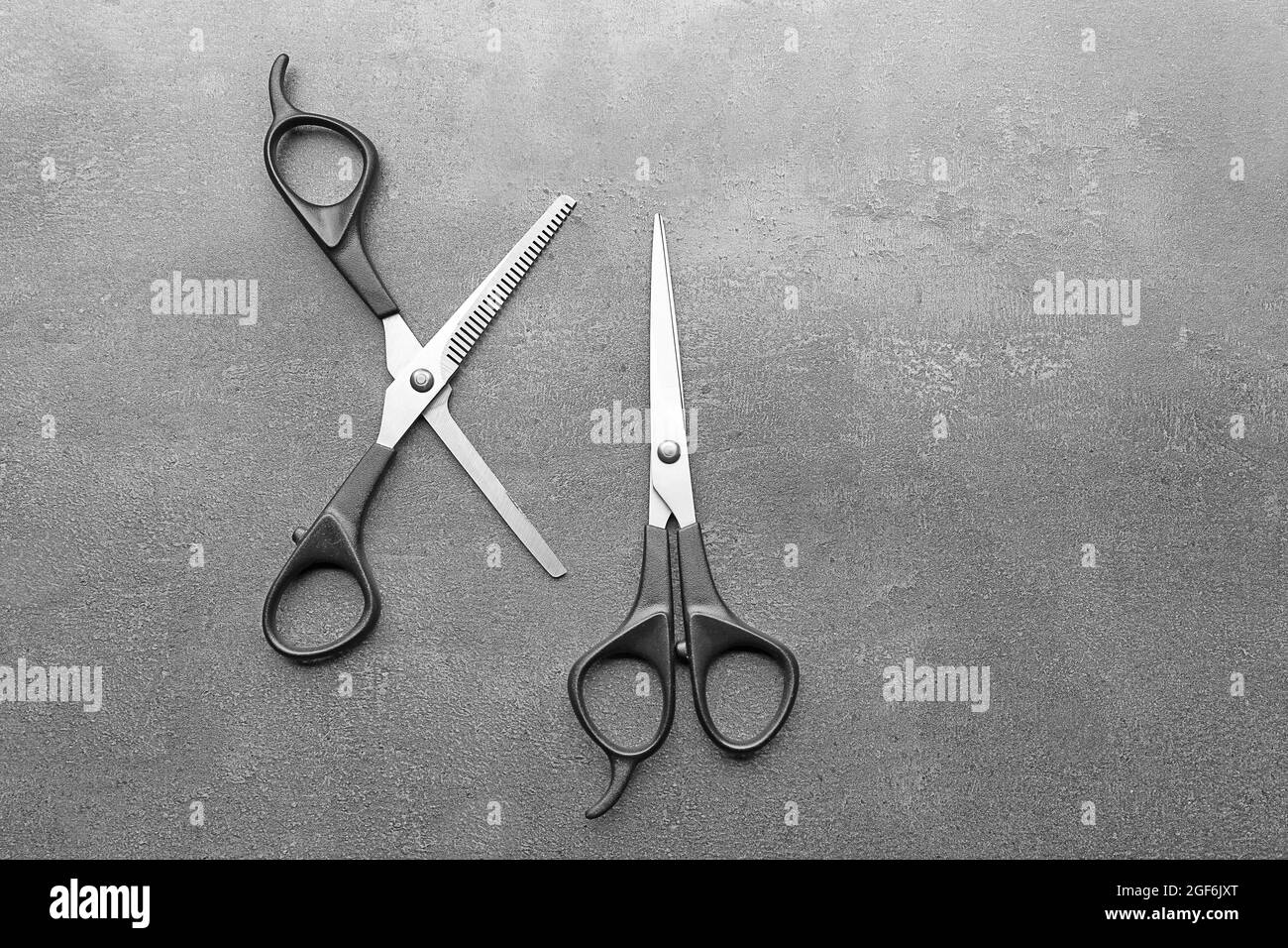 Professional scissors with black handles on a dark grey surface, top ...