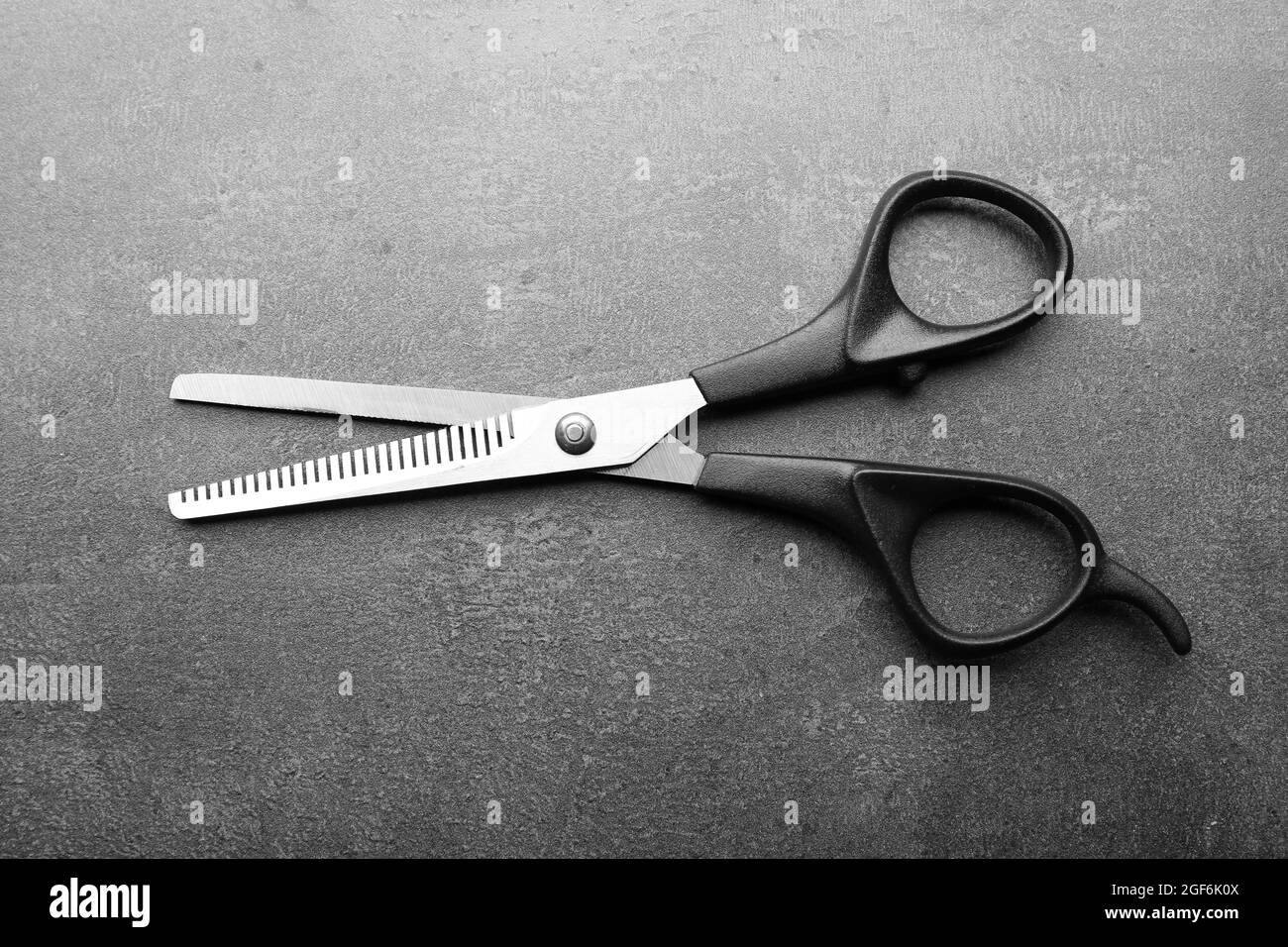 Professional scissors with black handles on a dark grey surface, top ...