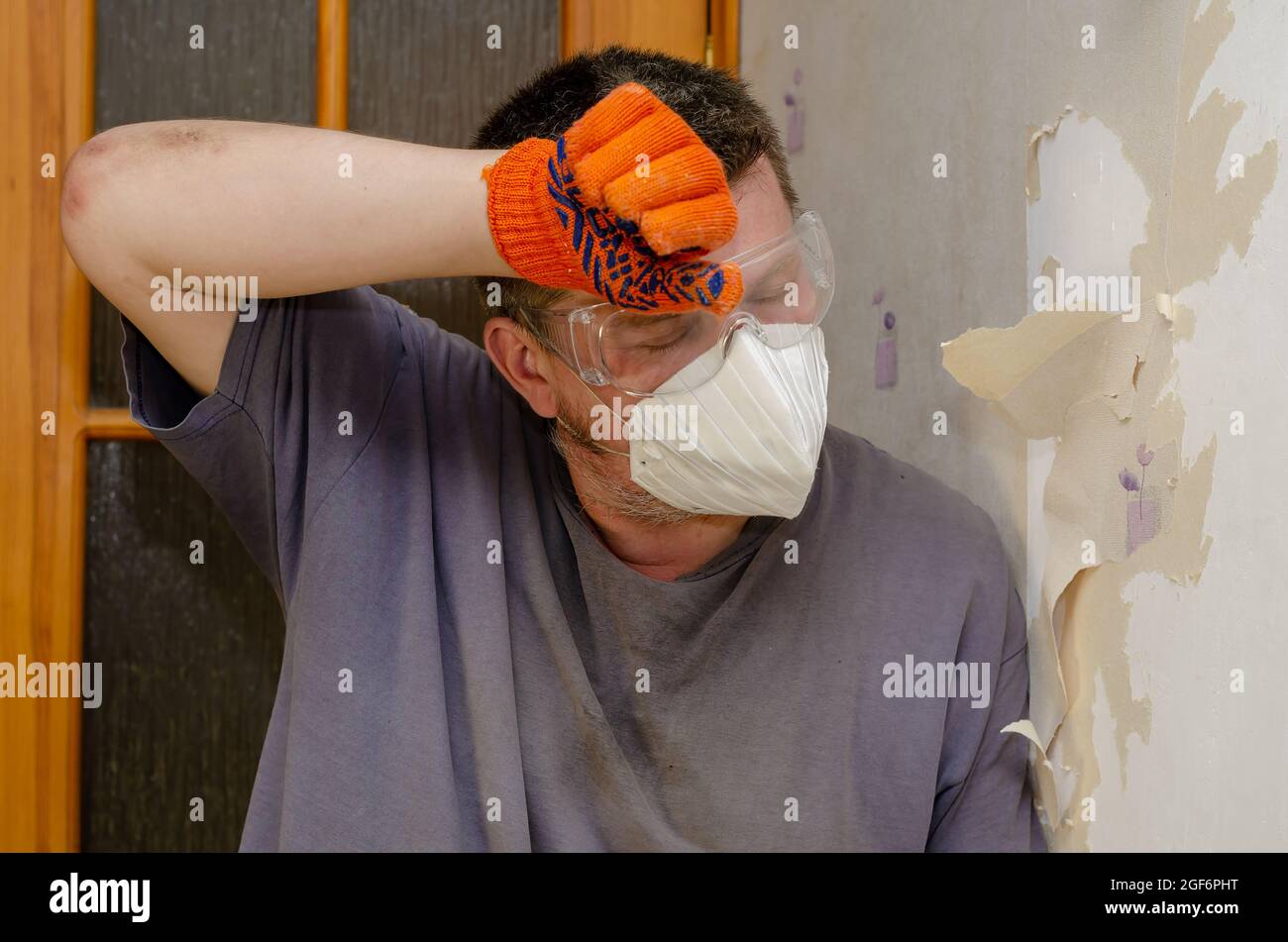 An adult male is wiping sweat from his forehead leaning against the ...