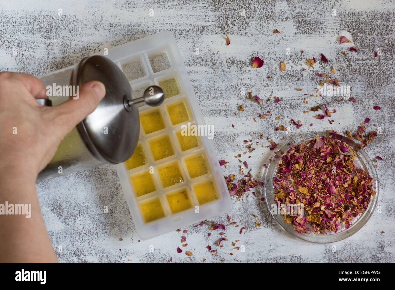 Woman hand pouring beverage made from brew dry rose petals for ice cube ...