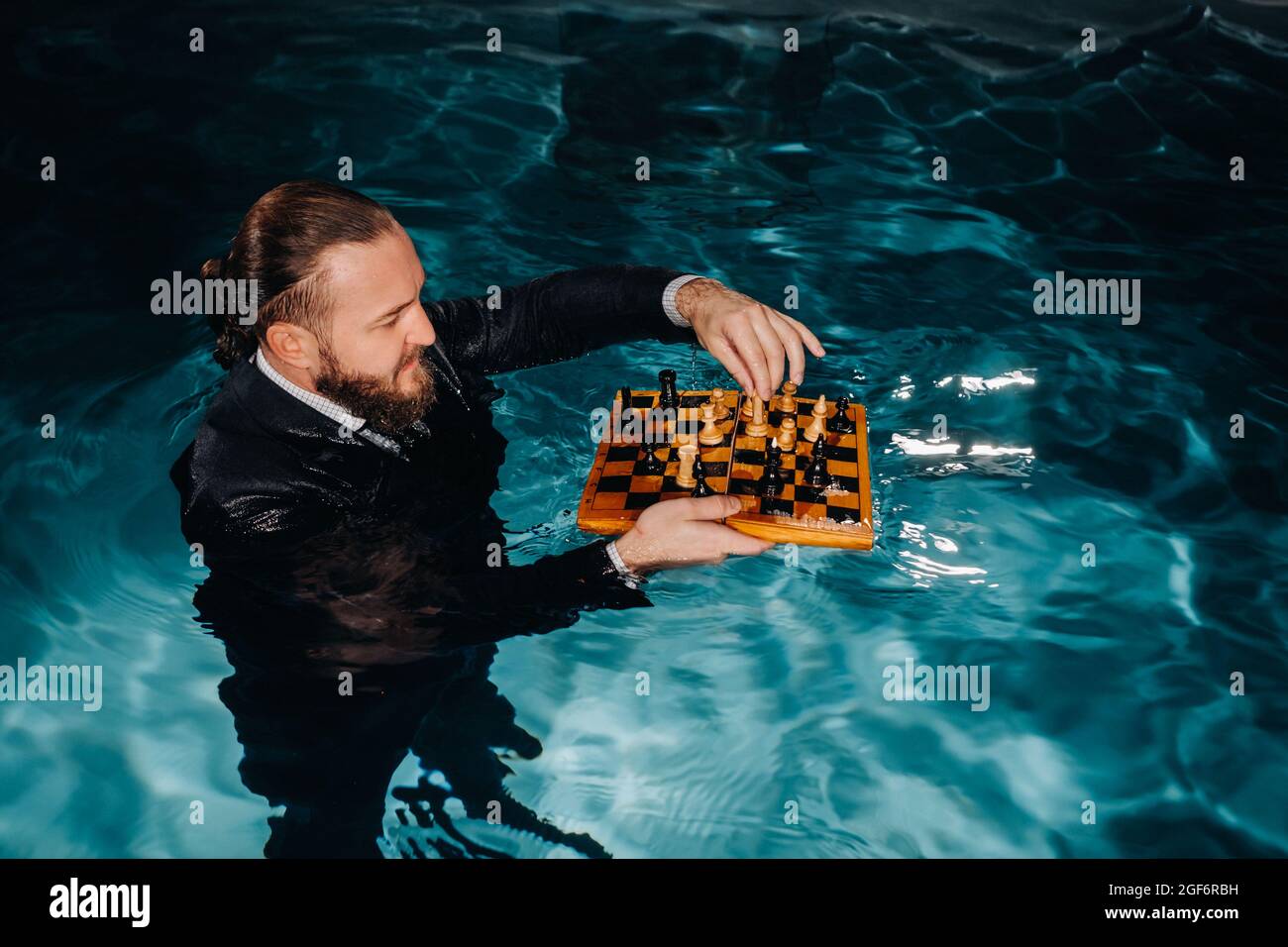 a man in a suit plays chess on the water in the pool Stock Photo - Alamy