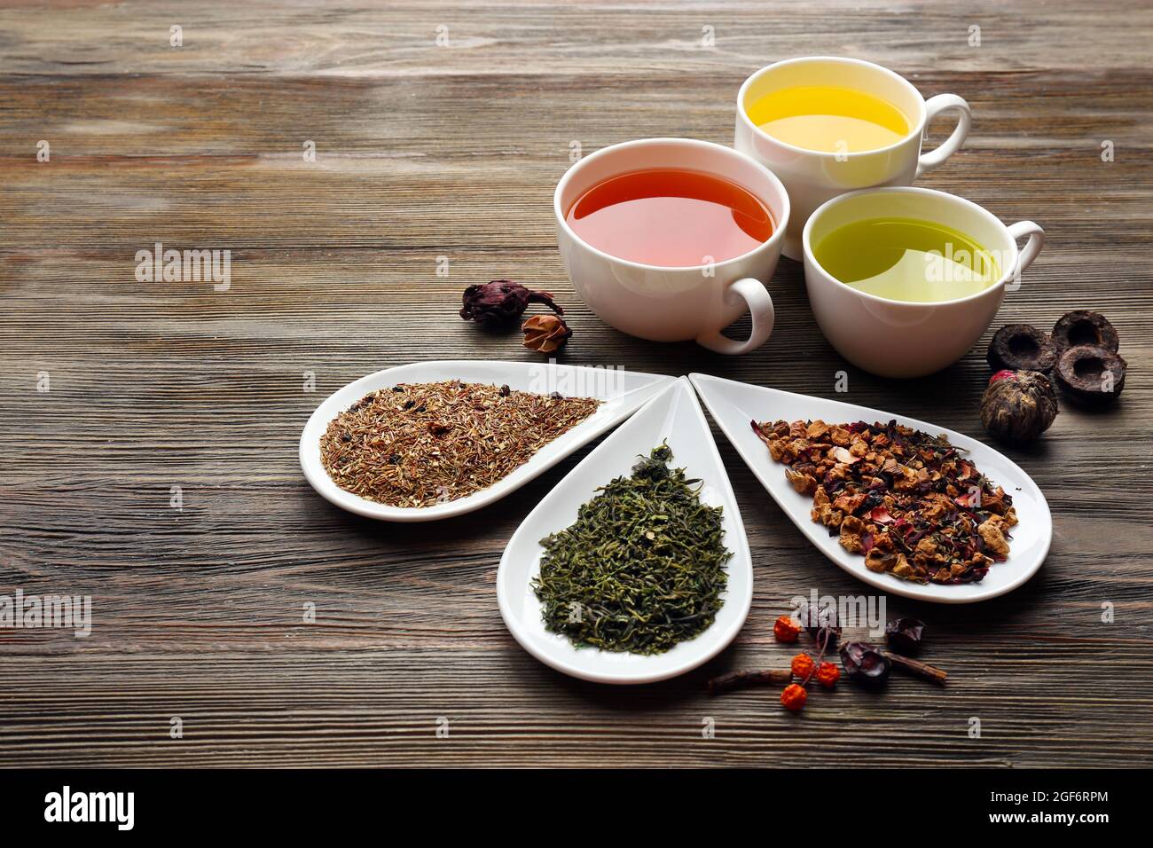 Tea concept. Different kinds of dry tea in ceramic bowls and cups of ...
