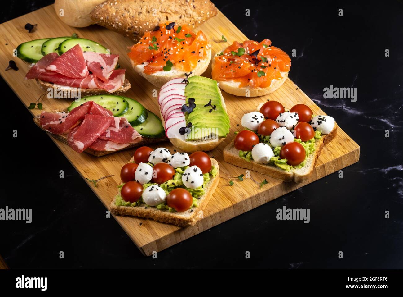 An assortment of sandwiches with fish, cheese, meat and vegetables lay ...