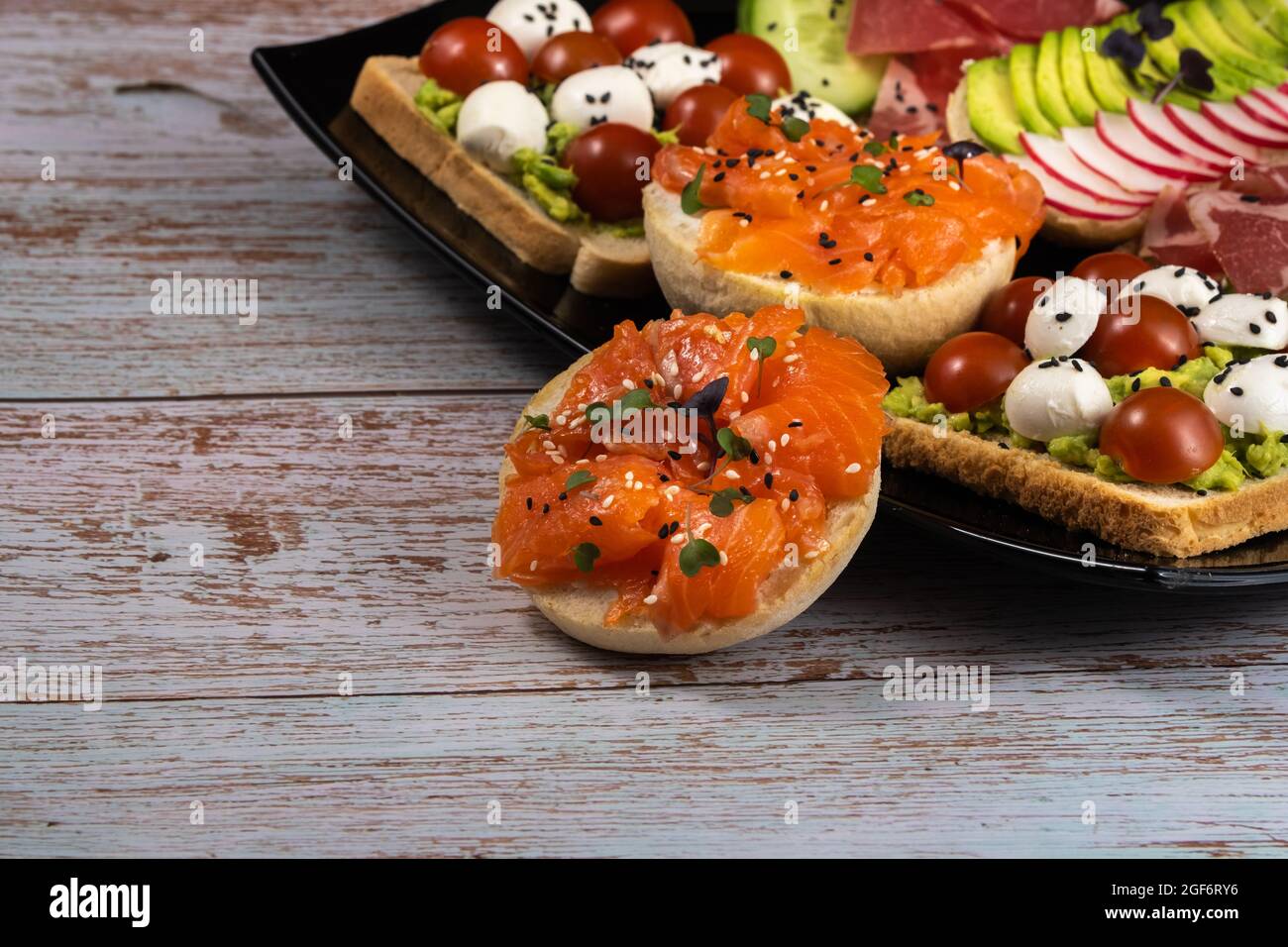 Assorted sandwiches with fish, cheese, meat and vegetables on a black ...