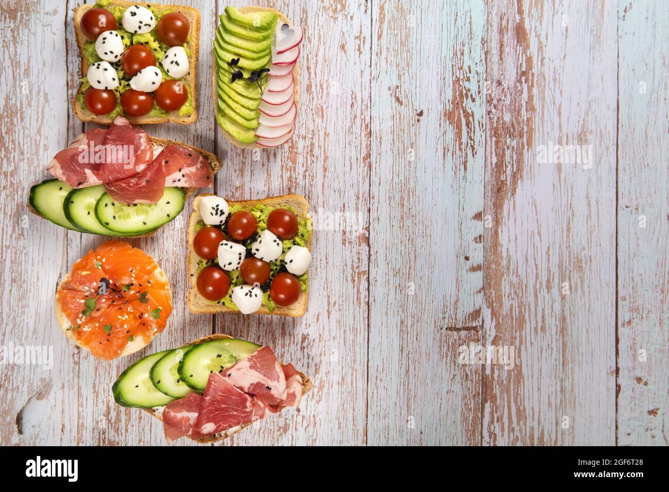 An assortment of sandwiches with fish, cheese, meat and vegetables lay ...