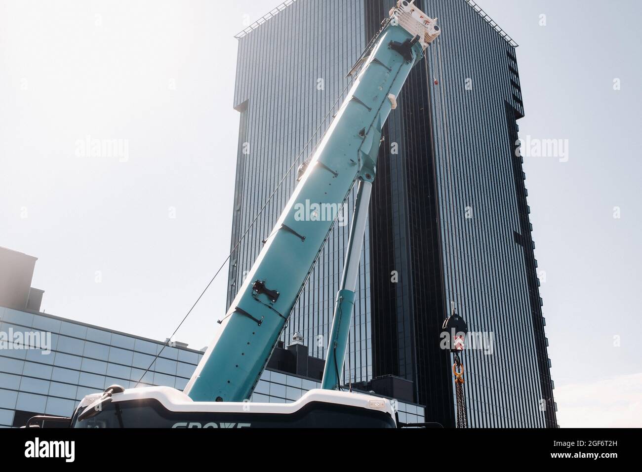 blue crane lifting mechanism with hooks near the glass modern building ...