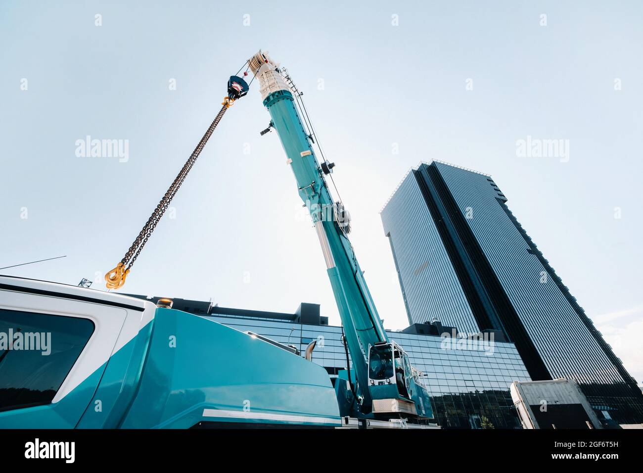 blue crane lifting mechanism with hooks near the glass modern building ...