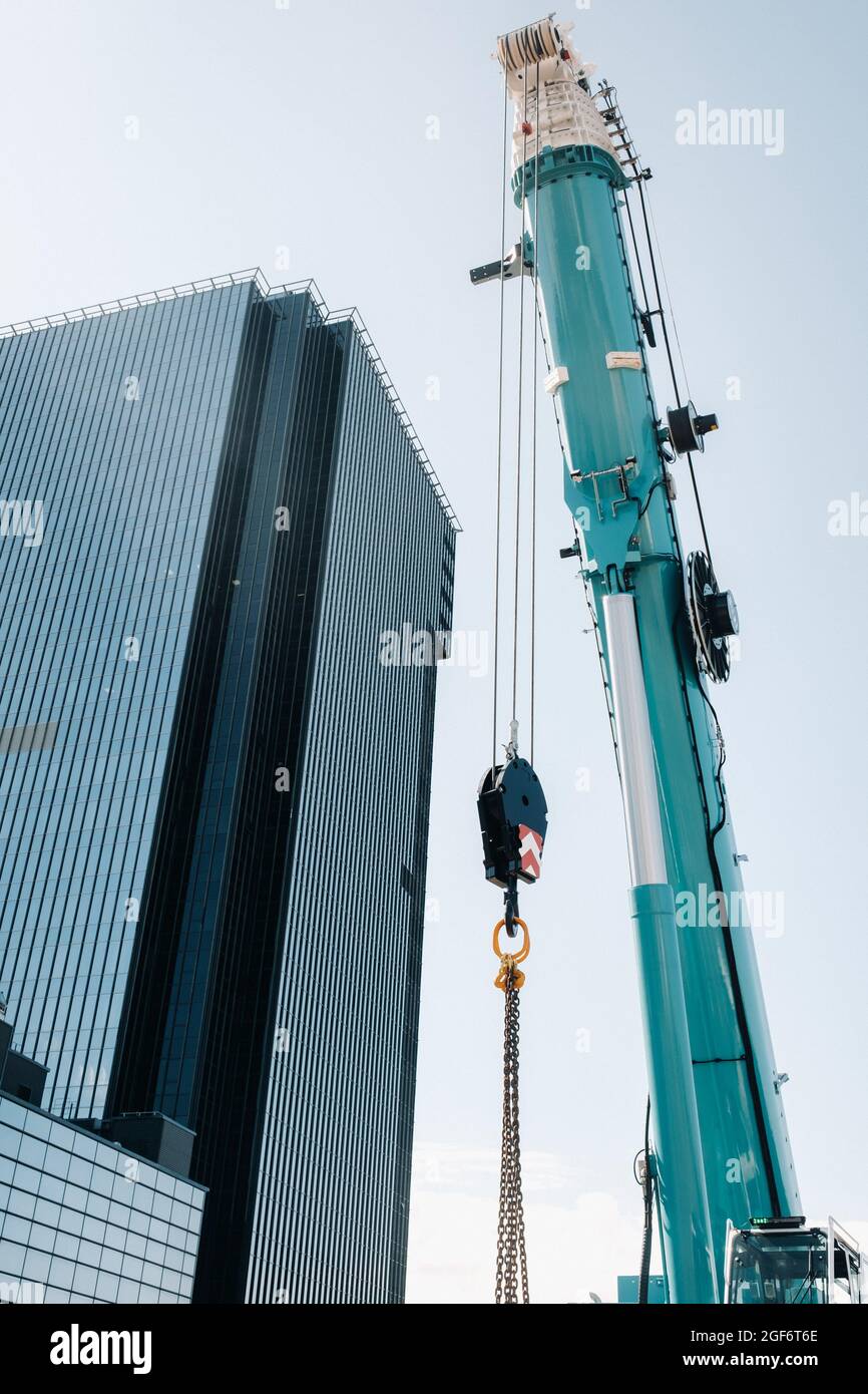 blue crane lifting mechanism with hooks near the glass modern building ...