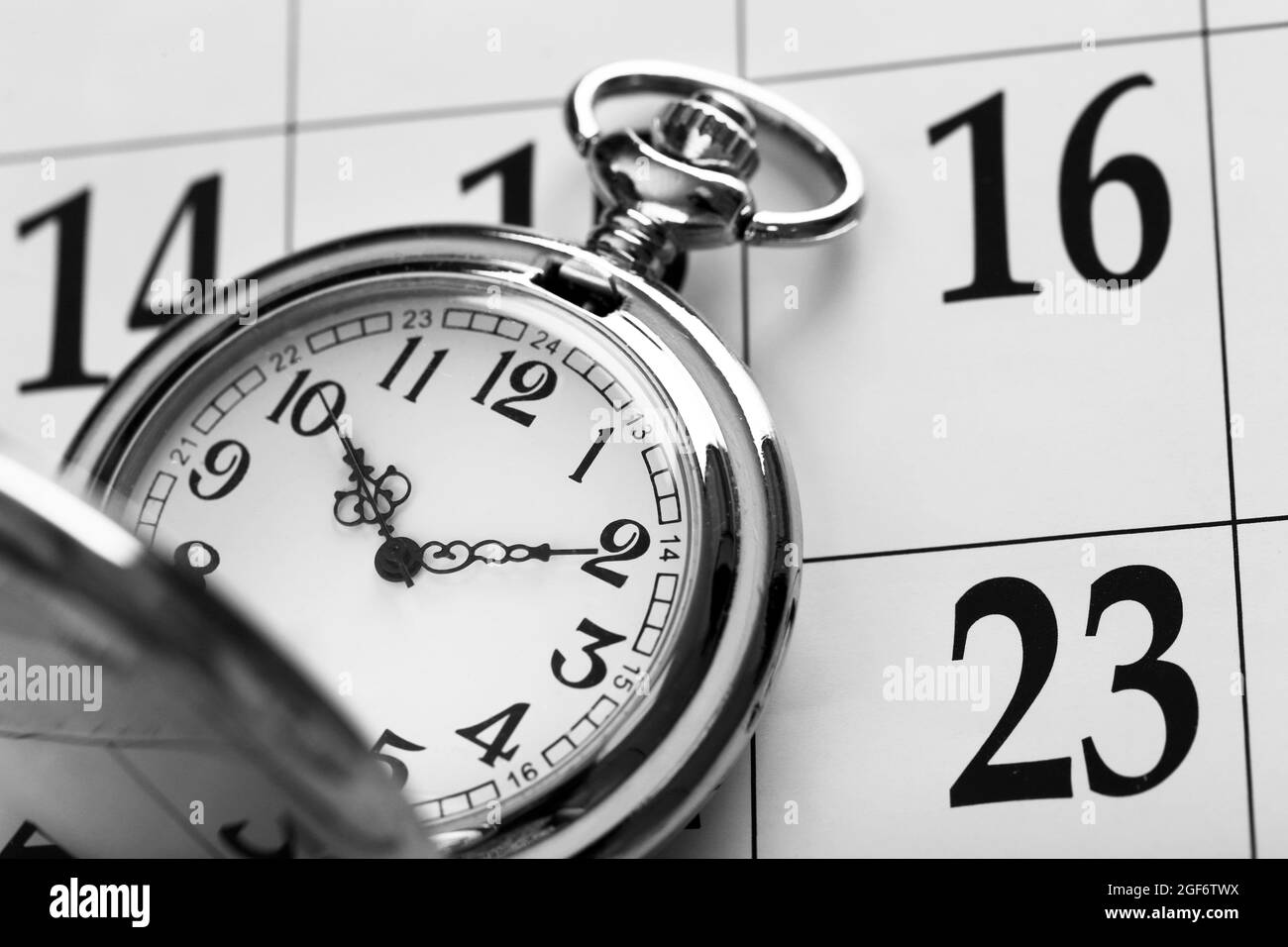 Vintage silver pocket watch laying on calender page with dates, close ...