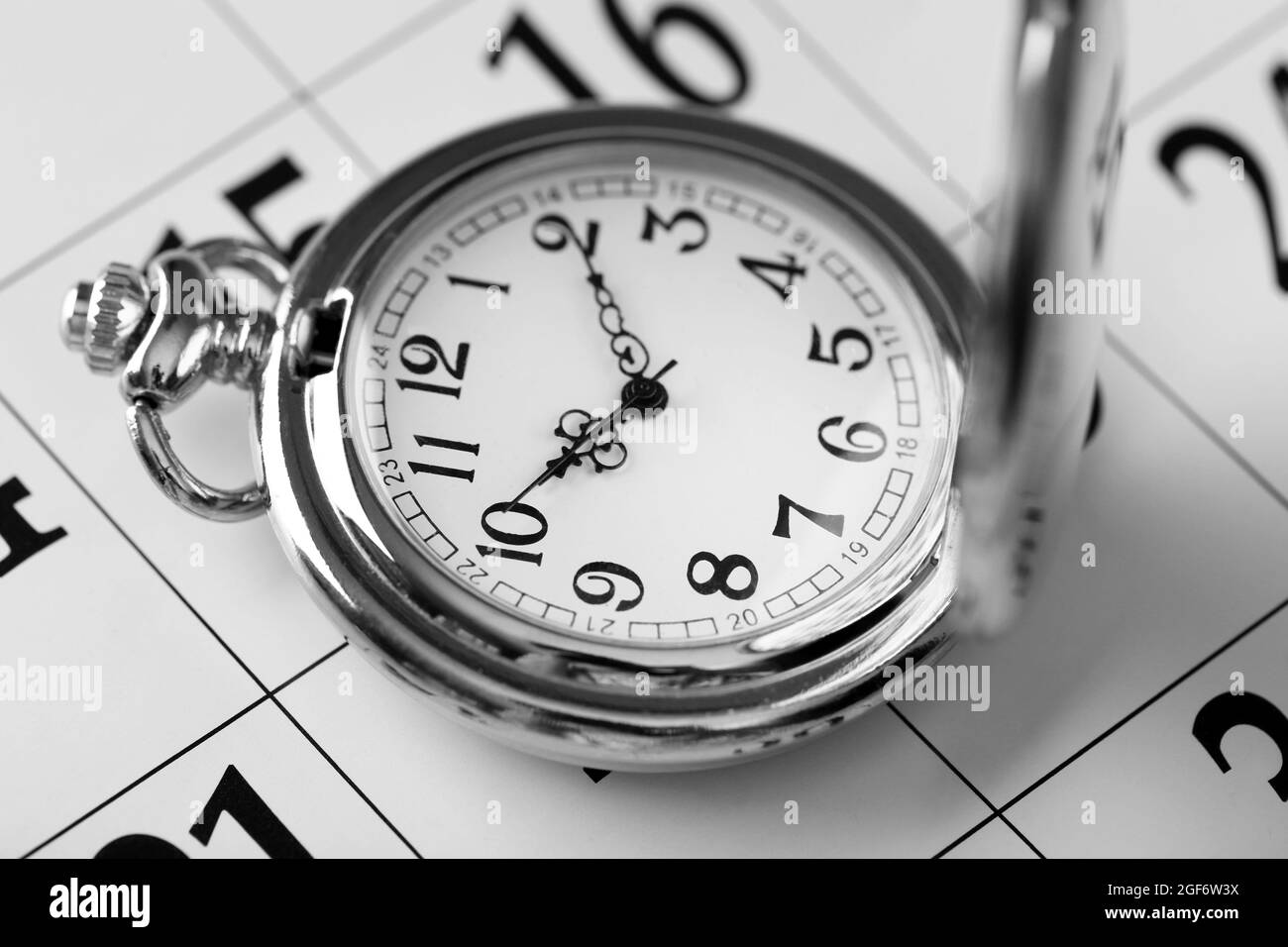 Vintage silver pocket watch laying on calender page with dates, close ...