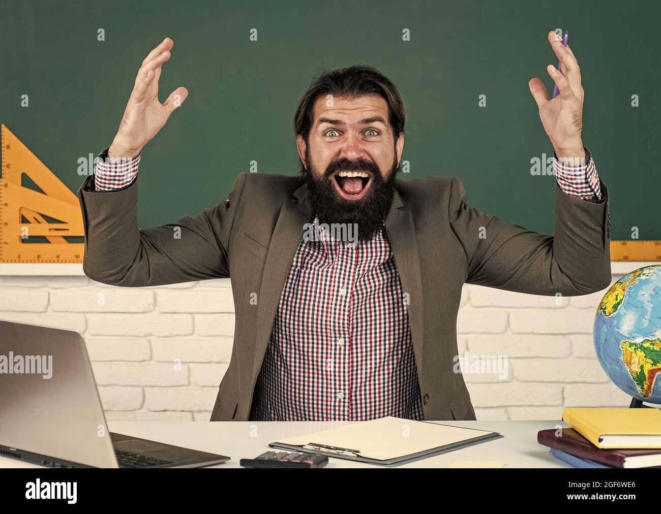 angry male teacher with laptop in classroom, education Stock Photo - Alamy