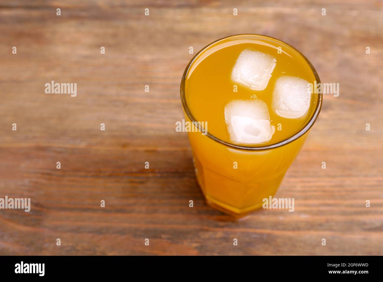 Glass of orange juice with ice block on wooden background Stock Photo ...