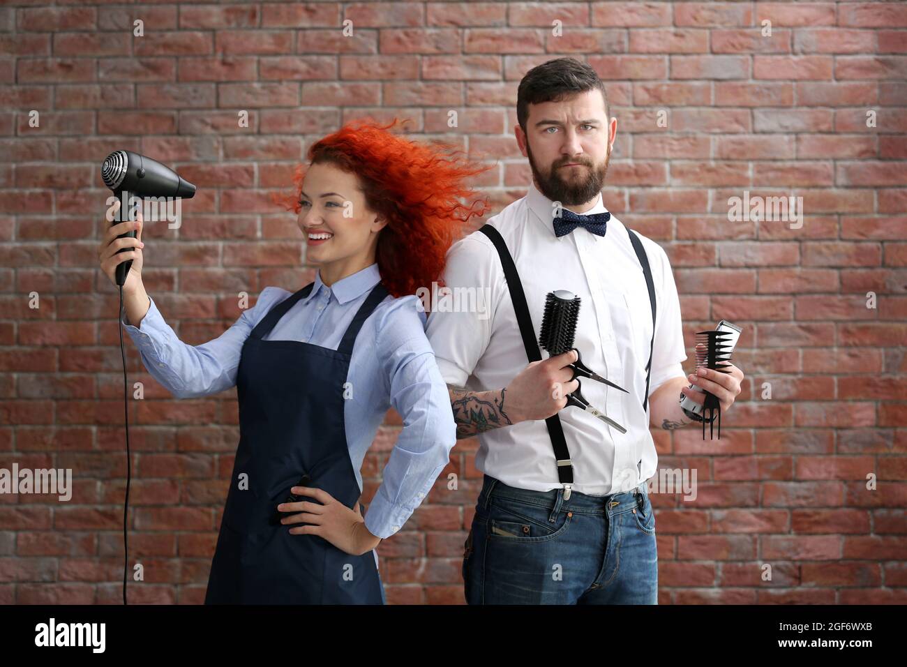 Two professional hairdressers on brick wall background Stock Photo - Alamy